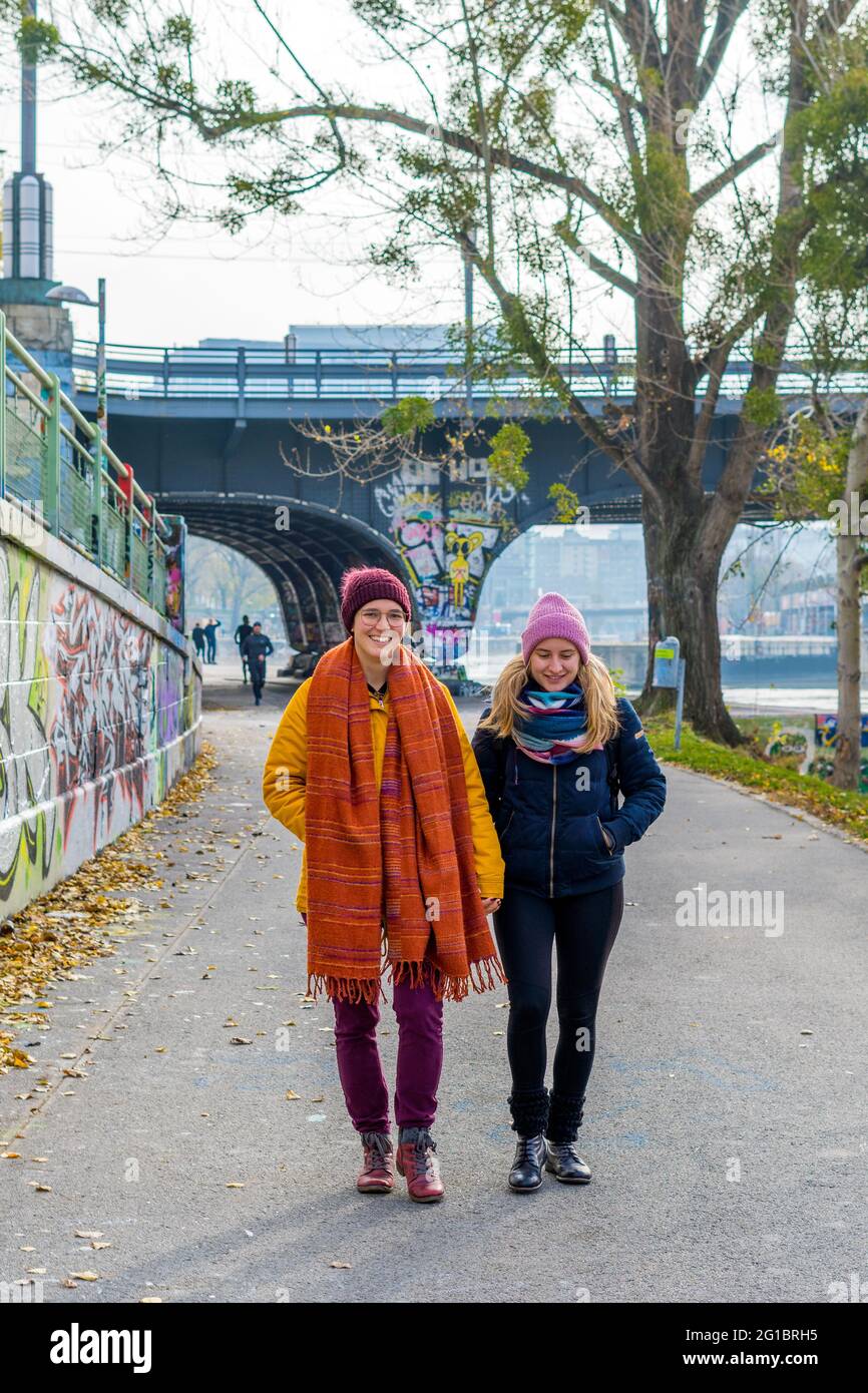 The two female friends holding hands while walking in the park, Austria ...