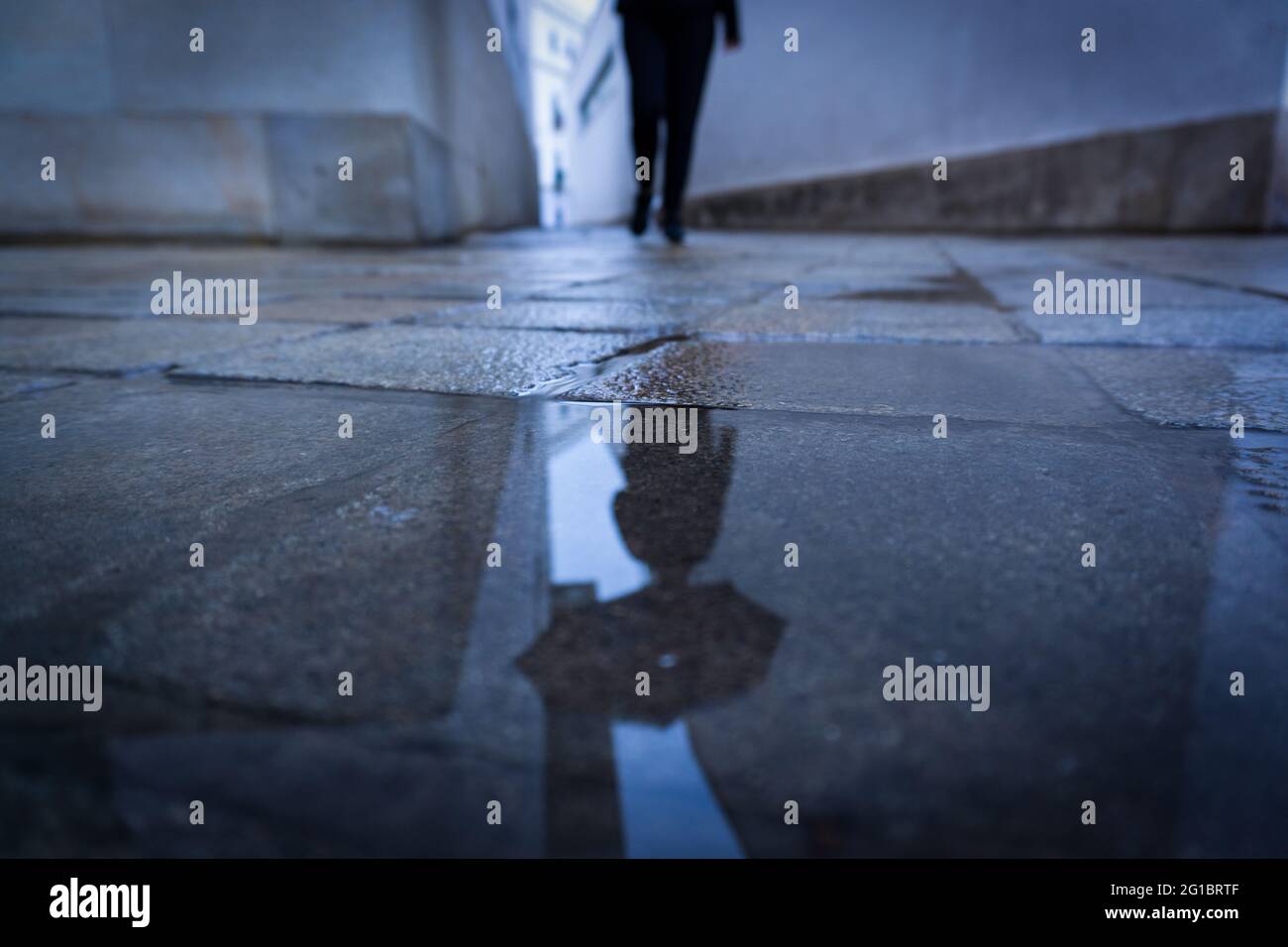 A reflection of a person with an umbrella in a puddle Stock Photo - Alamy