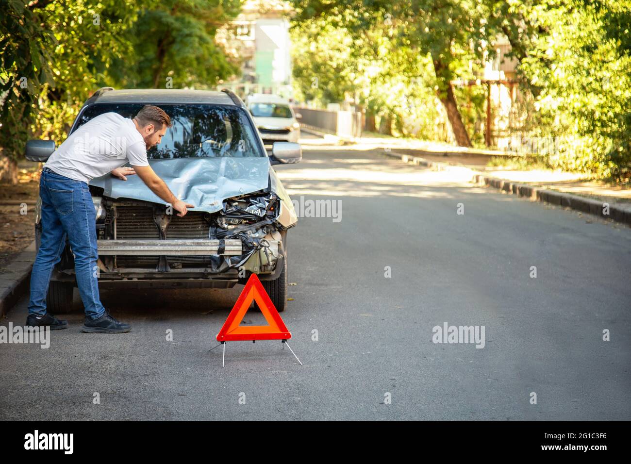 Man driver looking on Smashed broken car in accident. Red emergency ...