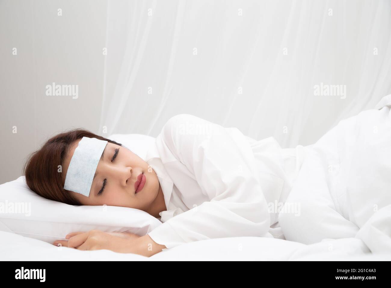 Young Asian woman with high fever while sleeping on white bed at home ...