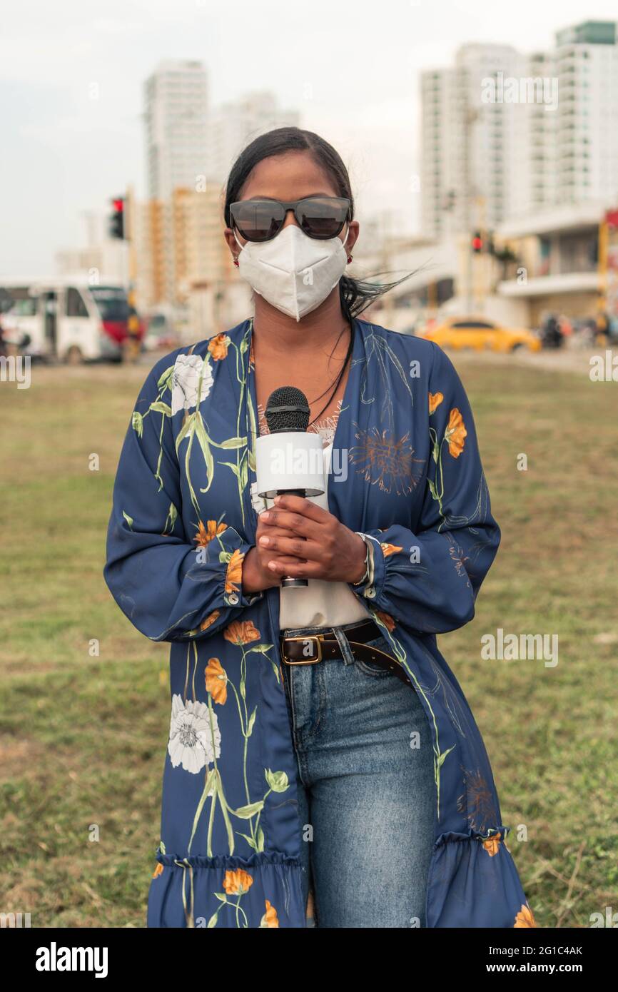 Journalist with face mask, sunglasses and microphone in the street ...
