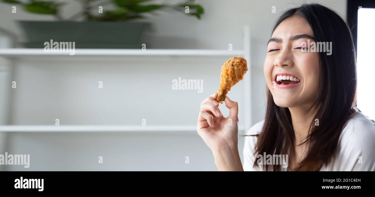 Young Asian woman eating chicken in the room at home and feeling ...