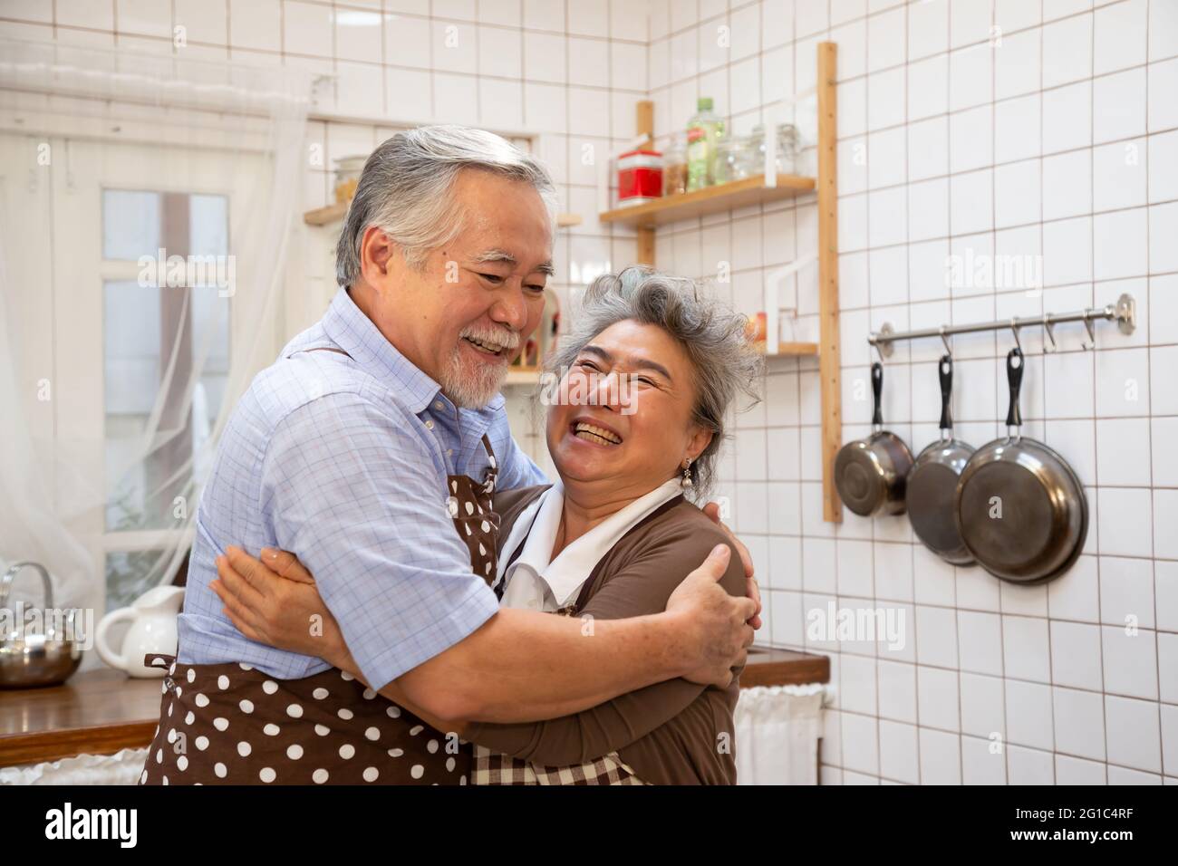 Asian grandpa hugs and smiling with grandma during cooking in kitchen ...