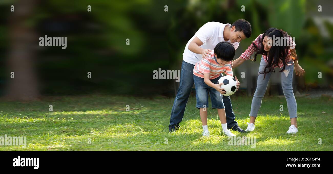 Family playing football or soccer in green garden together their ...