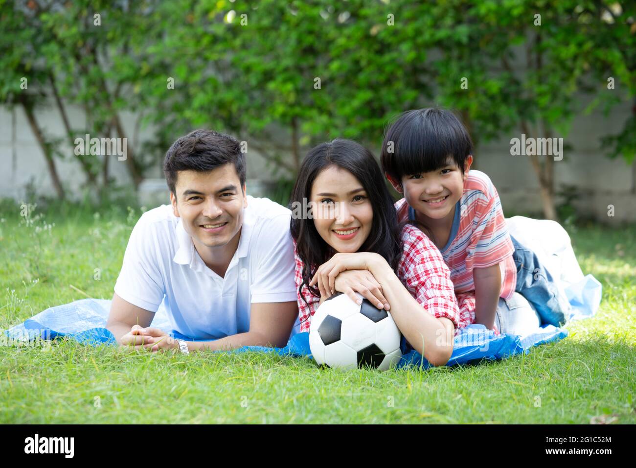 Family playing football or soccer in green garden together their ...