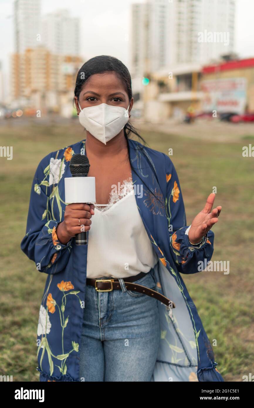 Hispanic woman journalist in mask holding microphone while on the ...