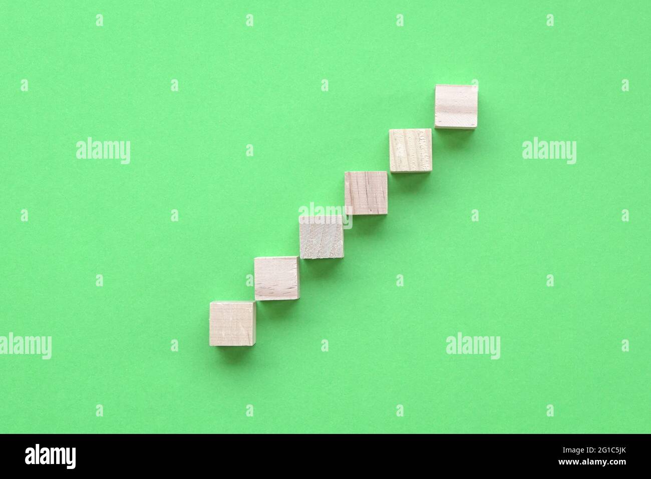 Wood block stacking as step stair. On green background. Business ...
