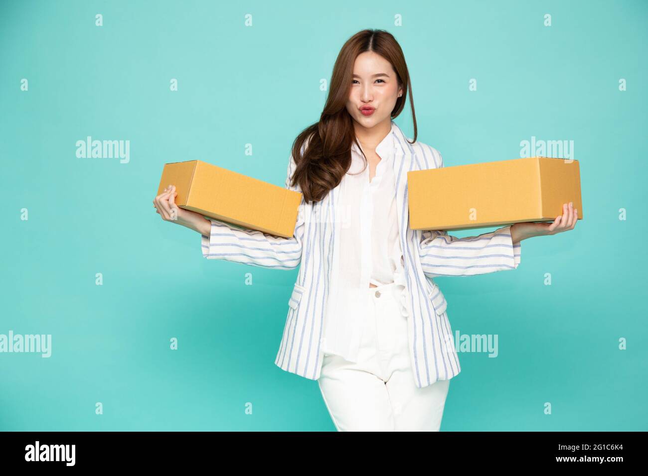 Happy Asian woman holding package parcel box isolated on light green ...