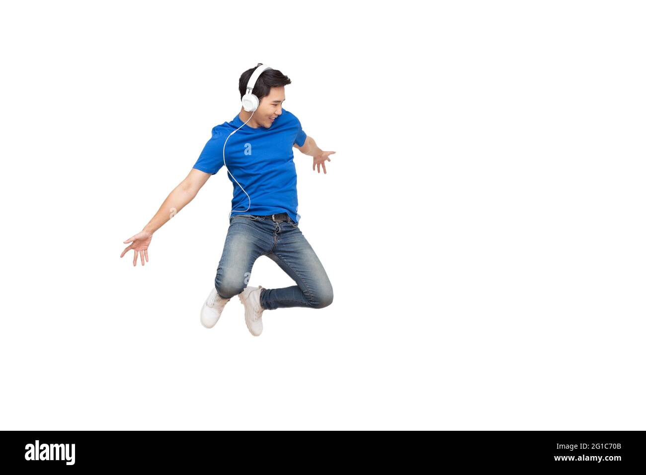 Young happy Asian man listening music and jumping with smile isolated ...