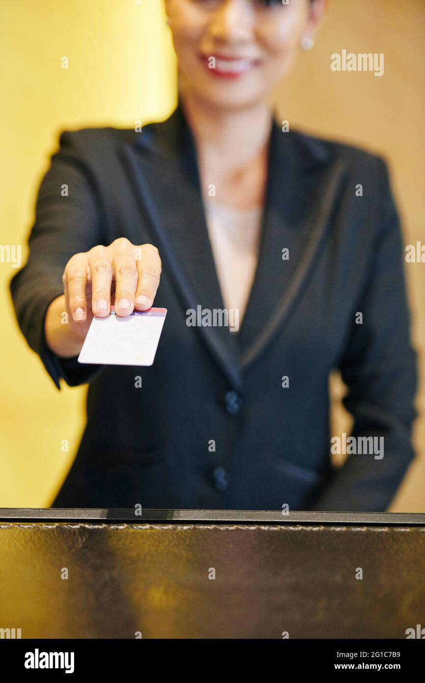 Positive female hotel receptionist giving electronic room key to hotel ...