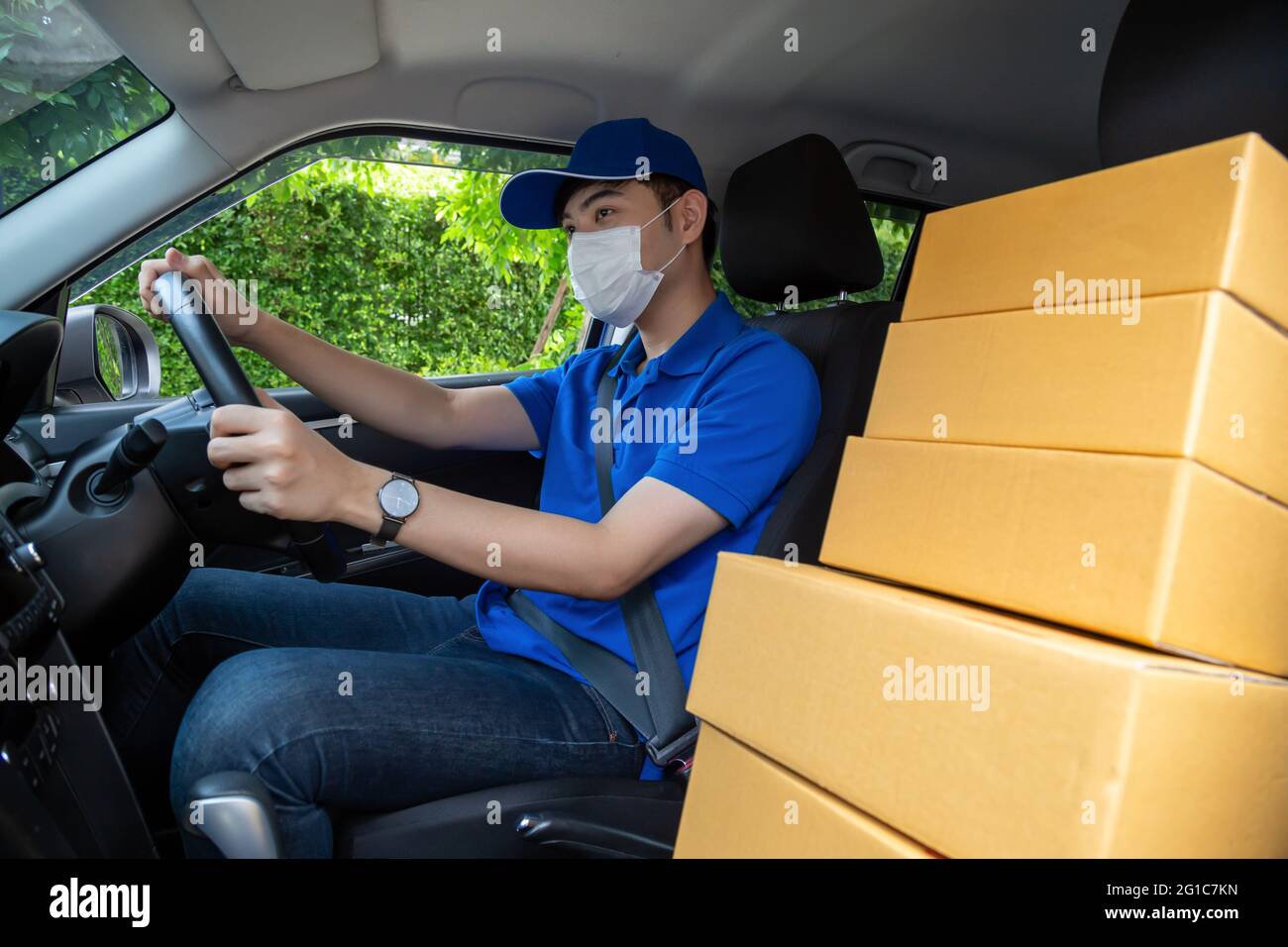 Asian Delivery man courier with face mask driving car delivering parcel ...