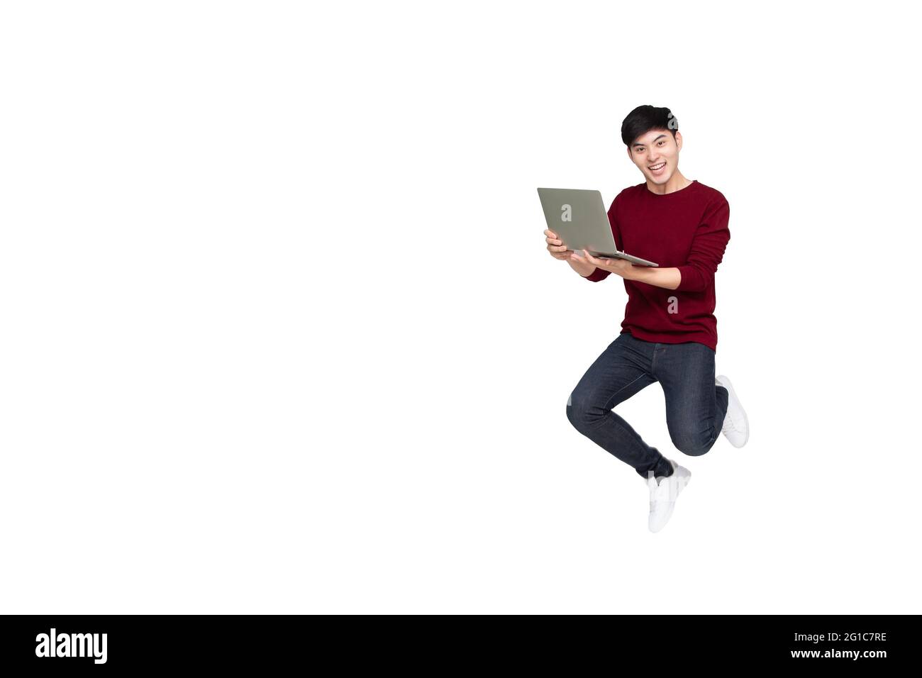 Excited Asian man jumping and holding laptop computer with celebrating ...