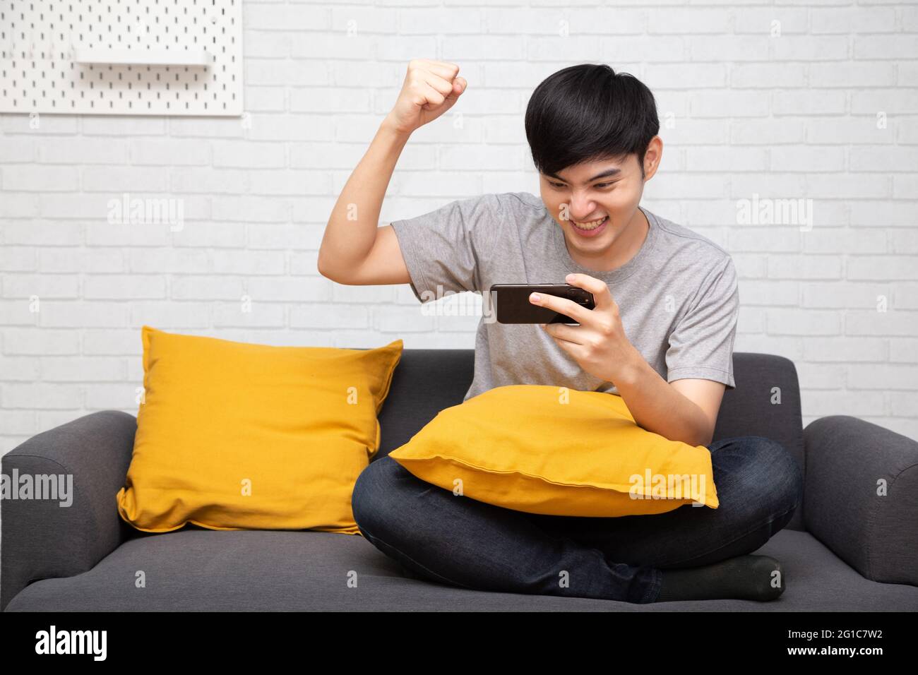 Young Asian man play game on mobile phone application and raising his ...