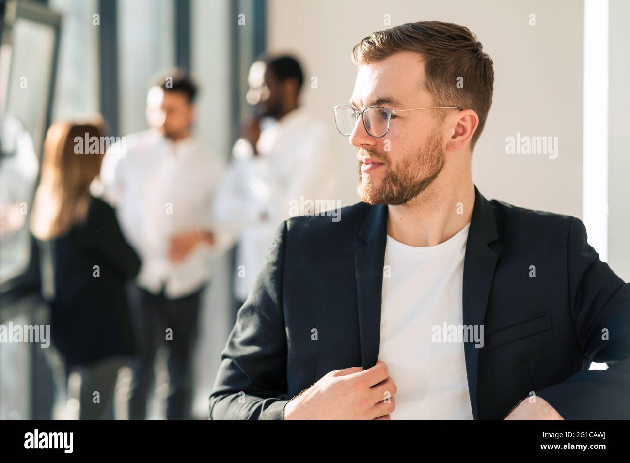 Portrait of serious man in the office and his colleagues behind Stock ...