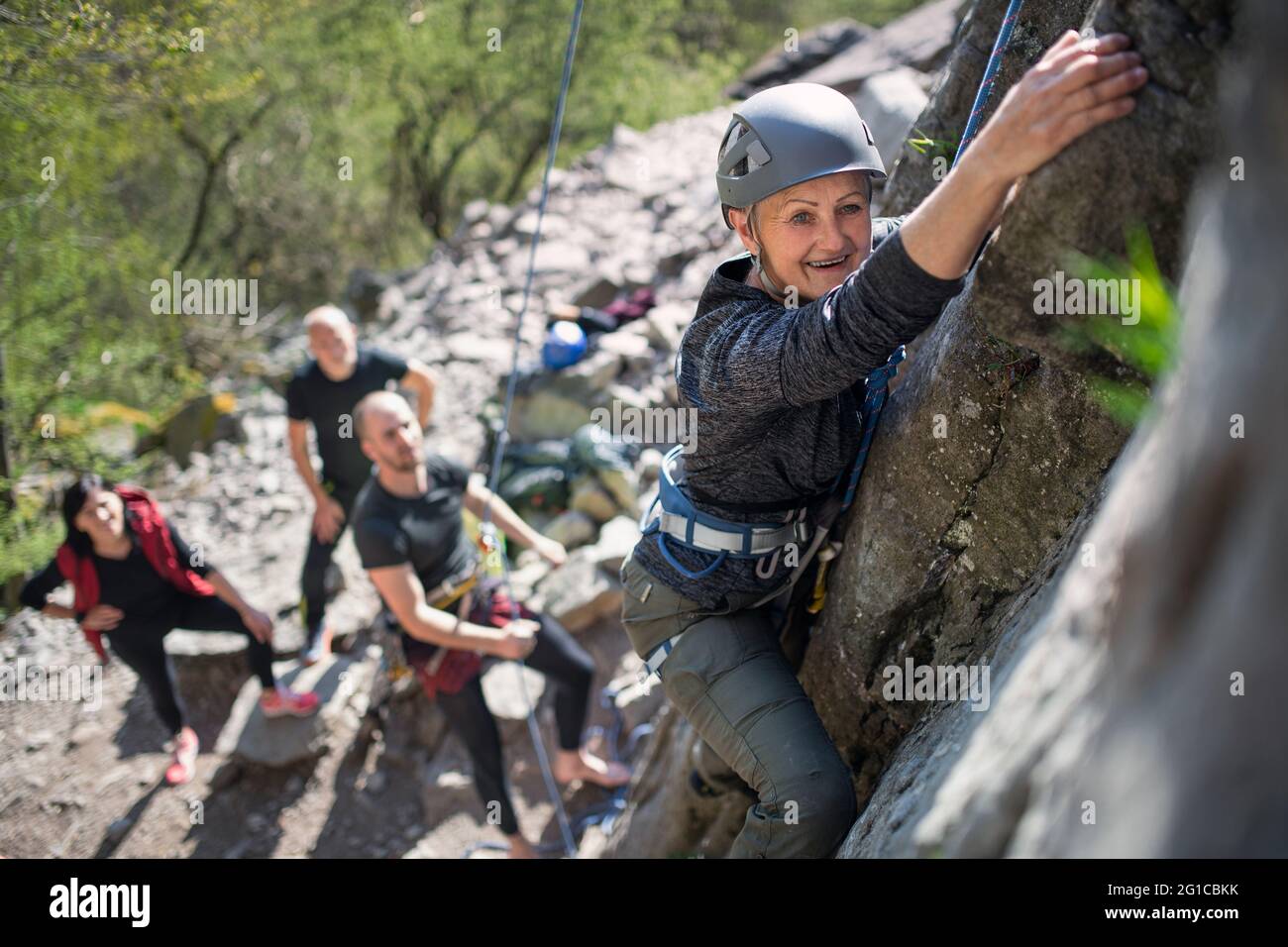 Group of seniors with instructor climbing rocks outdoors in nature ...