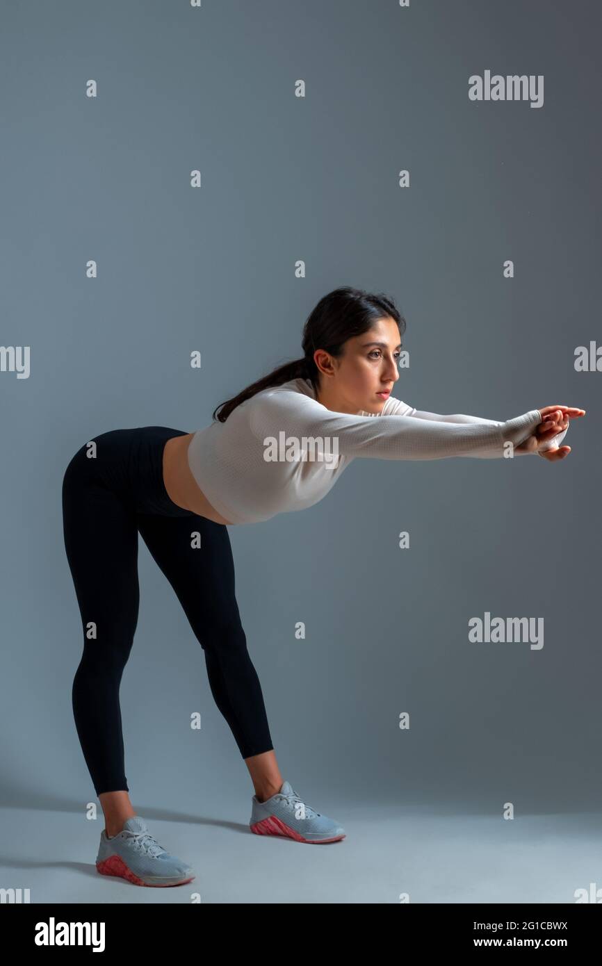 Girl bending body forward with outstretched arms on grey background ...