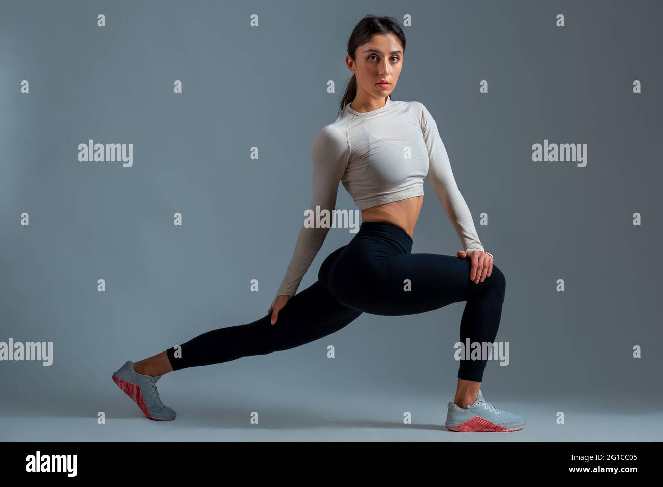 Girl performing forward lunge with body twist on grey background Stock ...