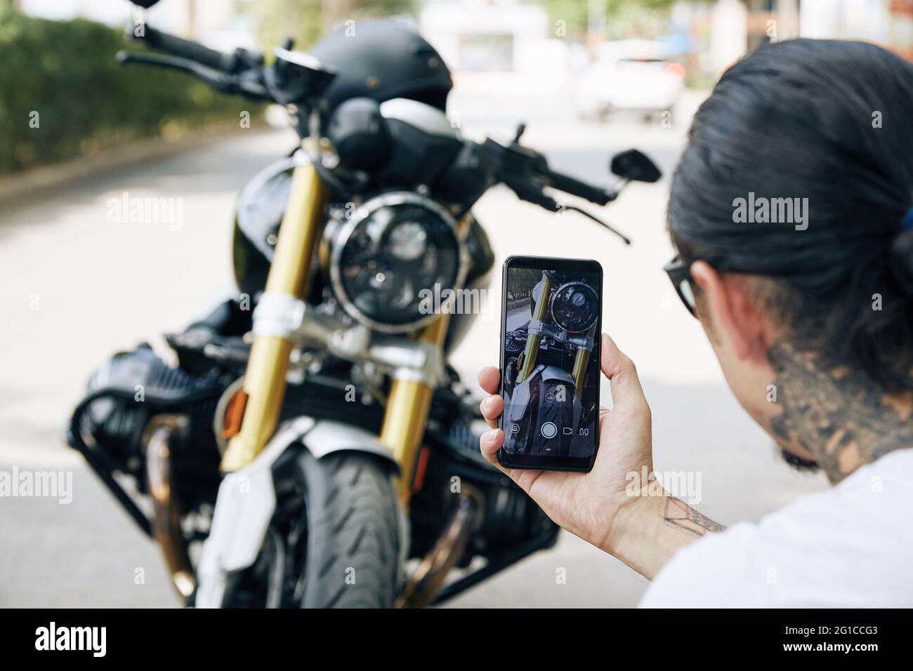 Man taking cool photos of his motorcycle on smartphone to share with ...