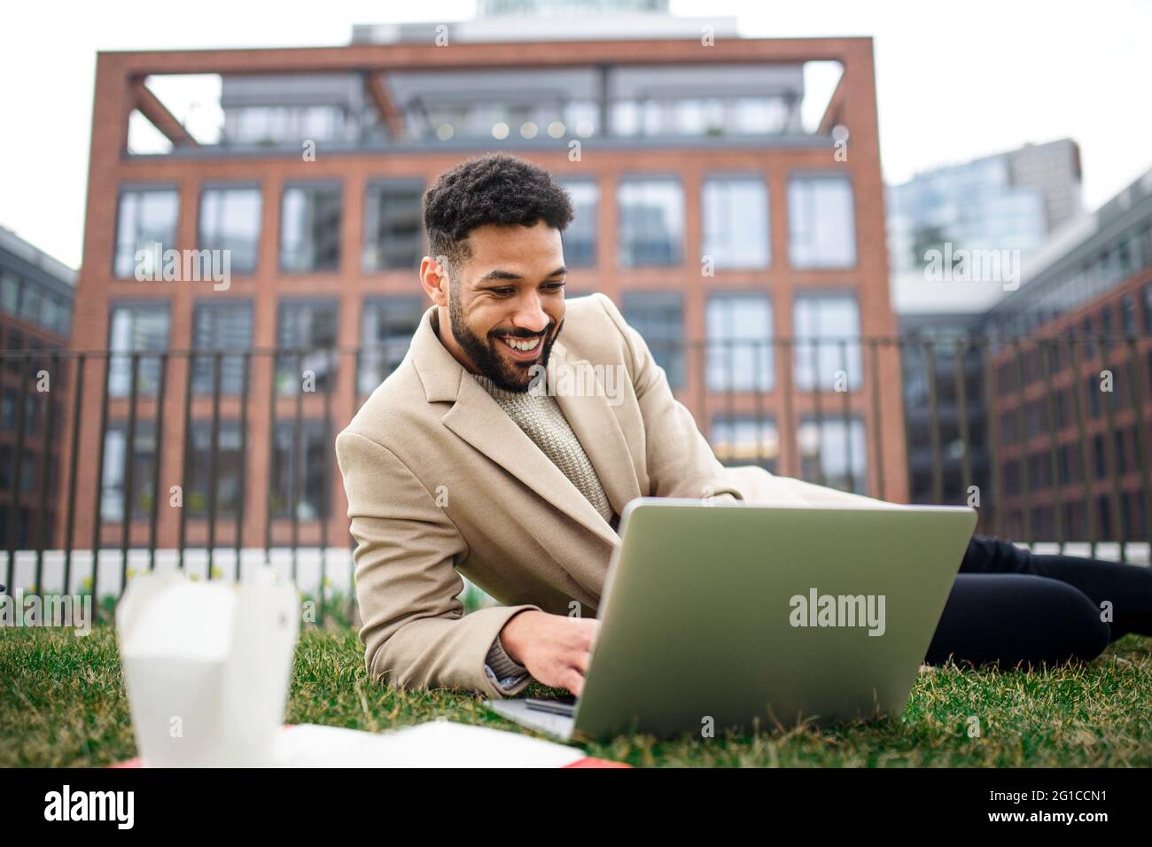 Man with laptop working outdoors in park in city, remote office concept ...