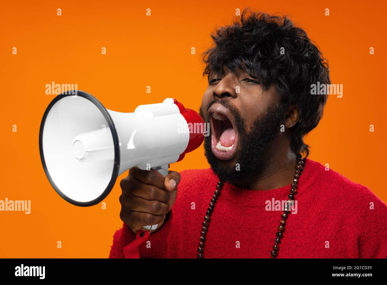 Young african american man in red hoodie screaming in megaphone against ...