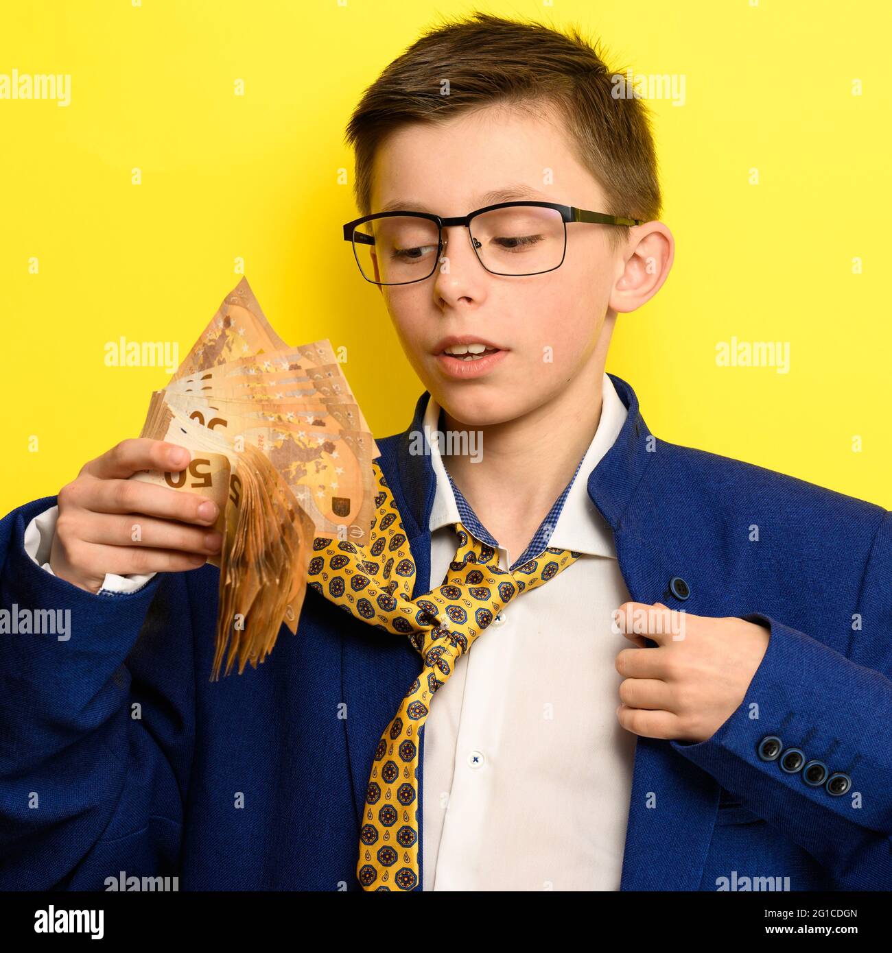 A child with a pathetic look holds in his hands euro bills, a boy in an ...