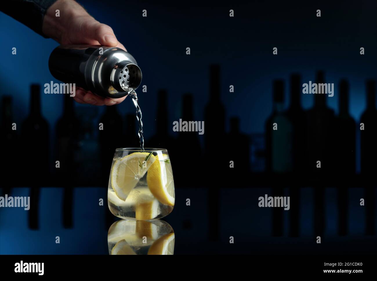 Cocktail "Gin-tonic" on a black reflective background. The bartender ...