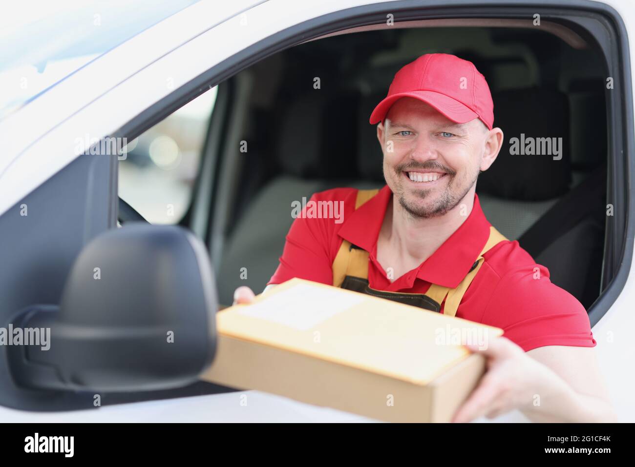 Delivery service driver offers package from his van Stock Photo - Alamy