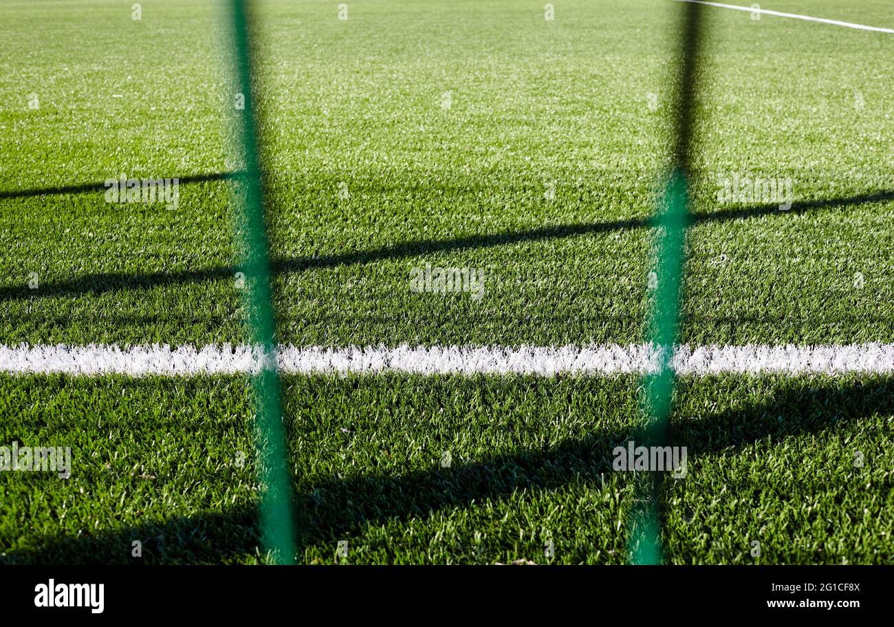 Lawn field for playing football behind the green fence mesh. Close-up ...