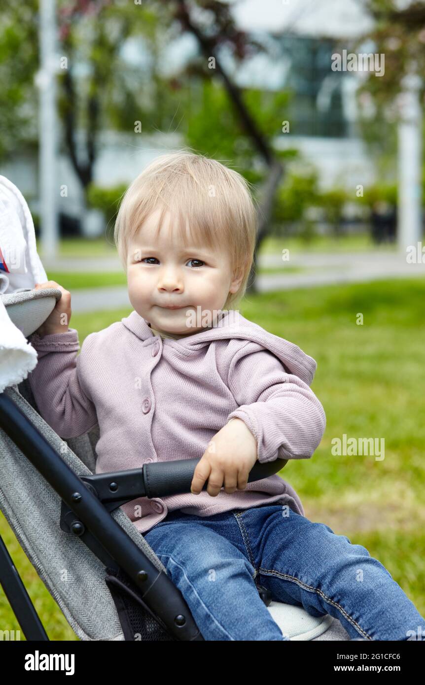 Baby in stroller on a walk in spring park. Adorable little girl in ...