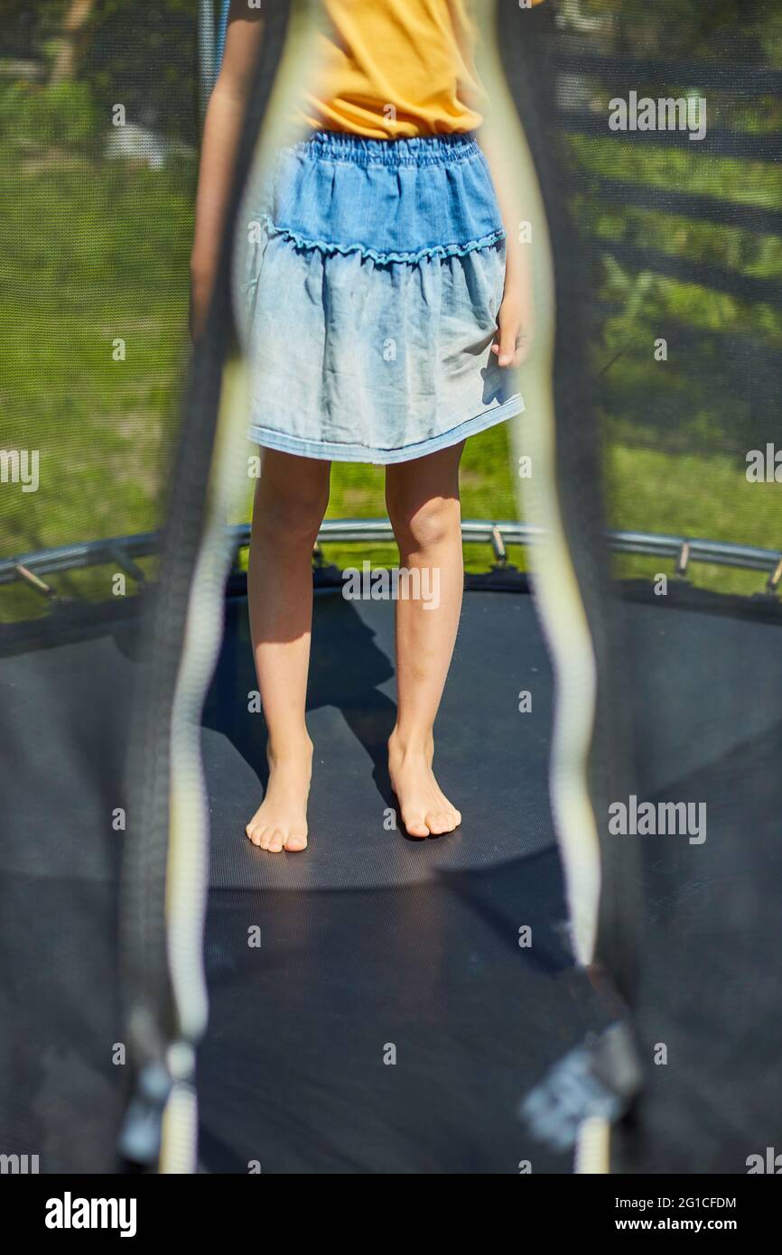 Leg of little child jumping on trampoline in the backyard of the house ...
