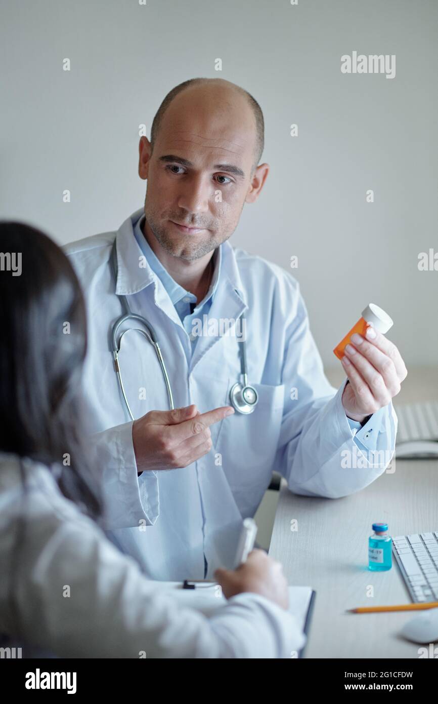General practitioner showing new medicine to colleague and explaining ...