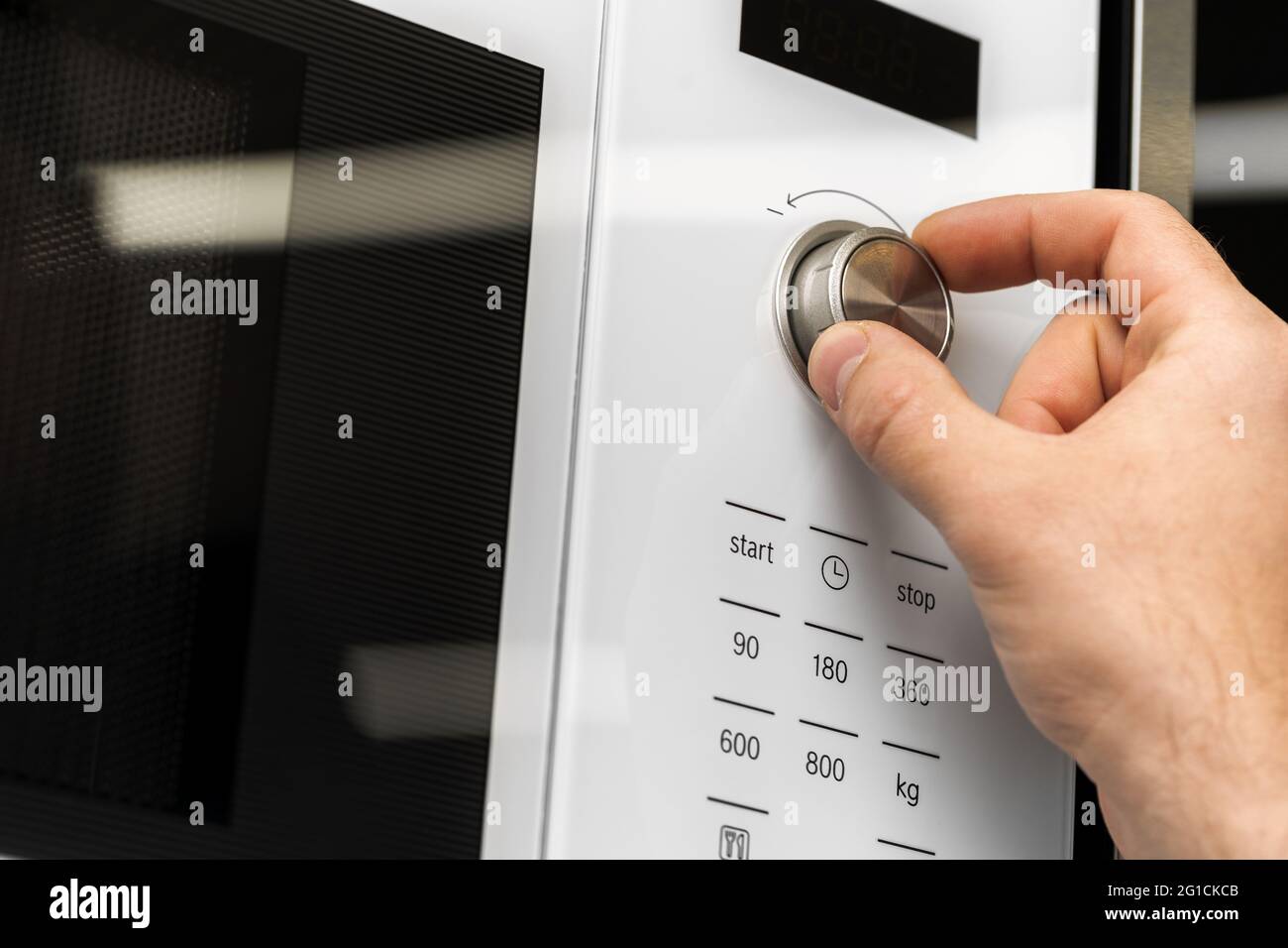 Hand pushing button of microwave oven for cooking food in kitchen Stock ...