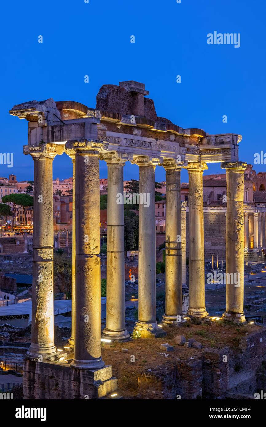 Temple of Saturn ruins with illuminated Ionic columns at dusk in Rome ...