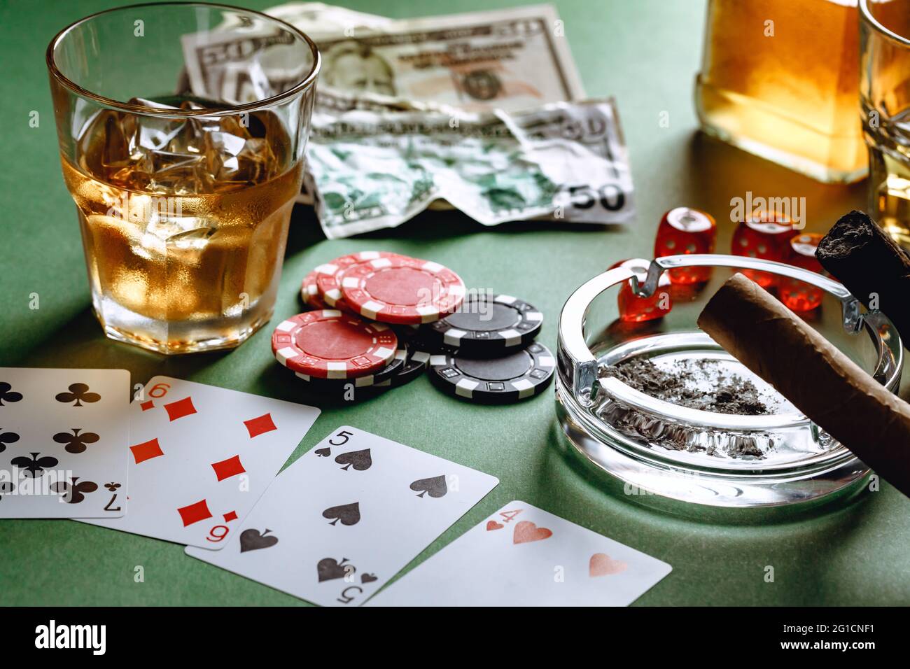 Glass of whiskey, cigar, playing cards and chips on green background ...