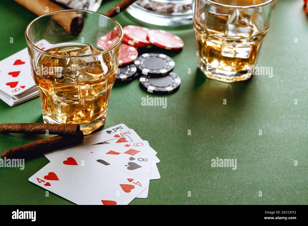 Glass of whiskey, cigar, playing cards and chips on green background ...