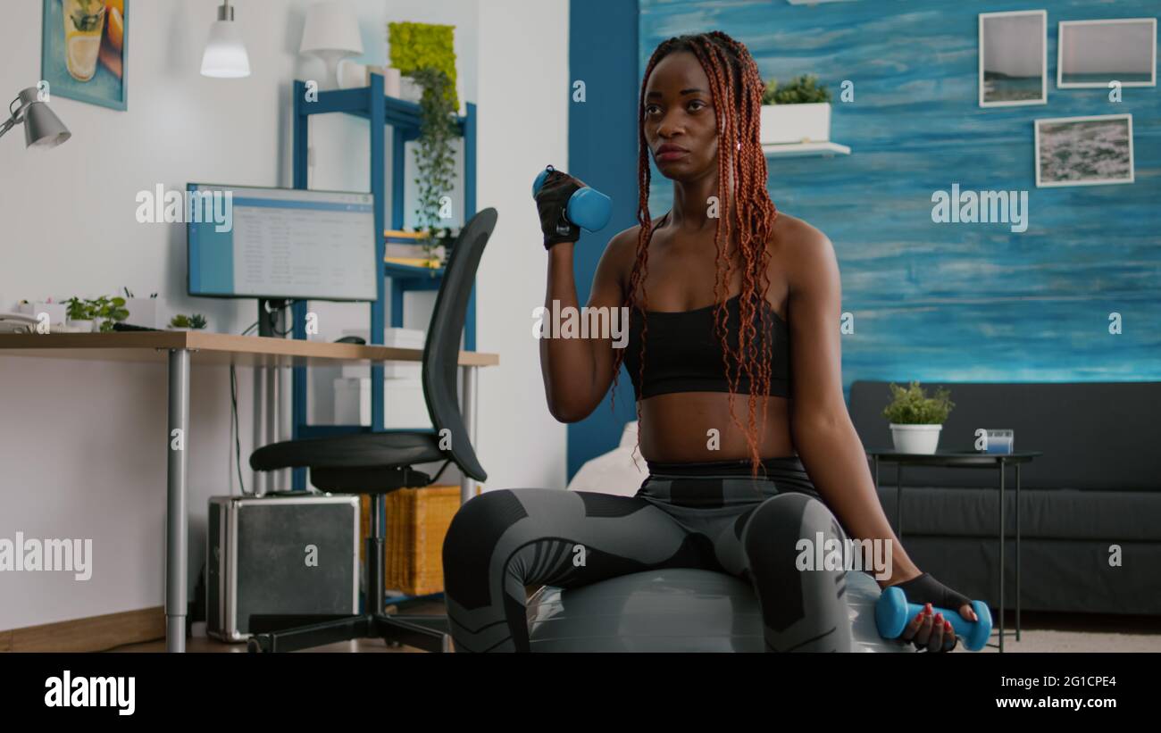 Fit athletic woman with dark skin doing muscle exercises with fitness ...