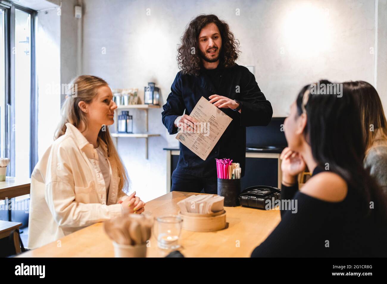 Waiter talking with female customers while taking order in restaurant ...