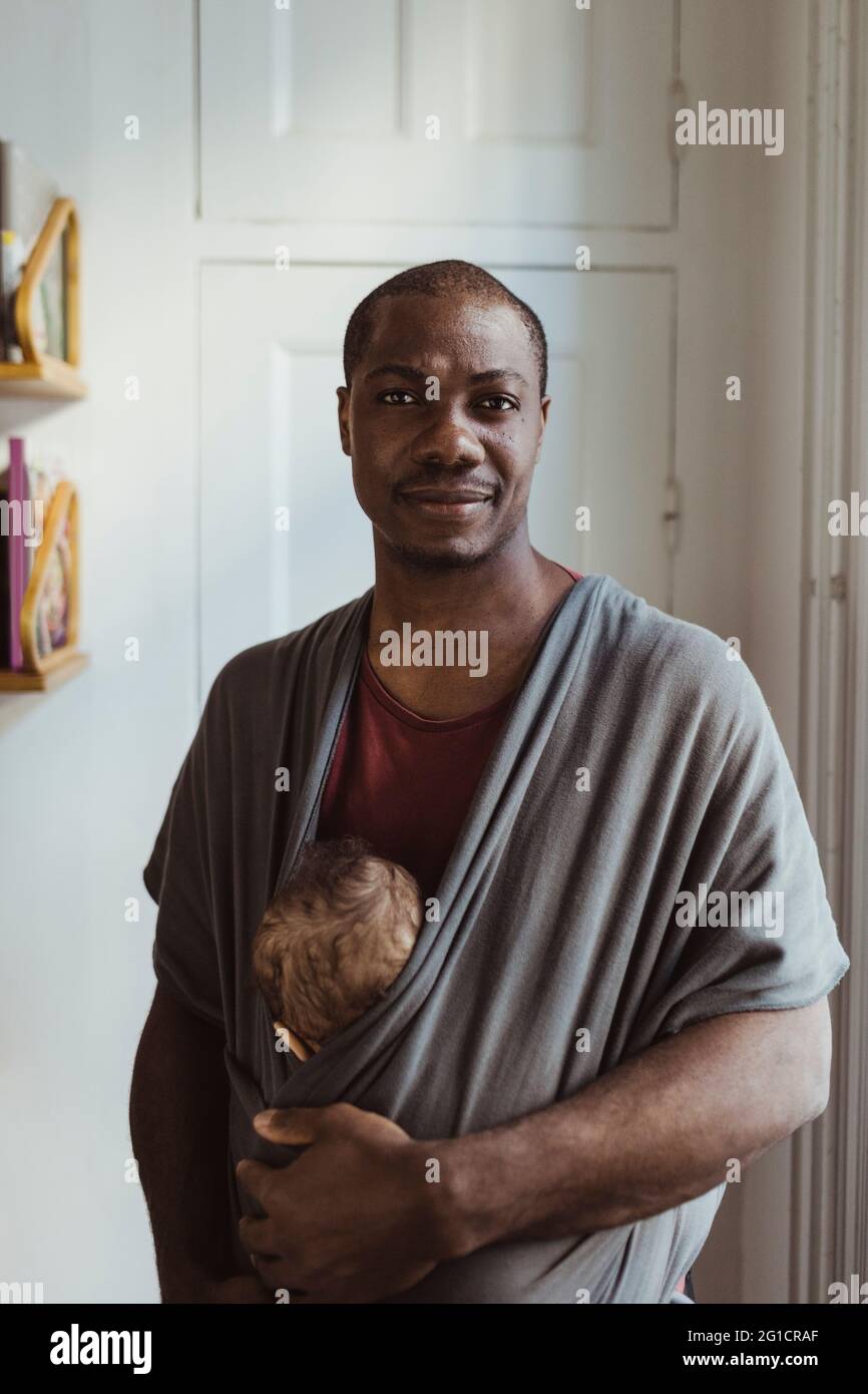 Portrait of man with baby boy in carrier at home Stock Photo - Alamy