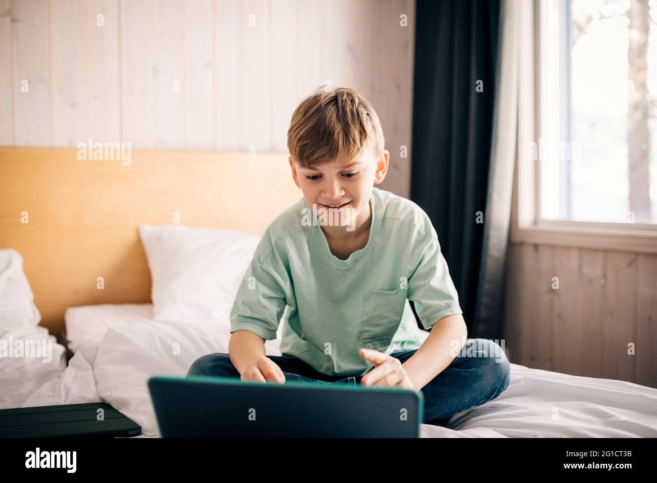 Blond boy E-learning through laptop at home Stock Photo - Alamy