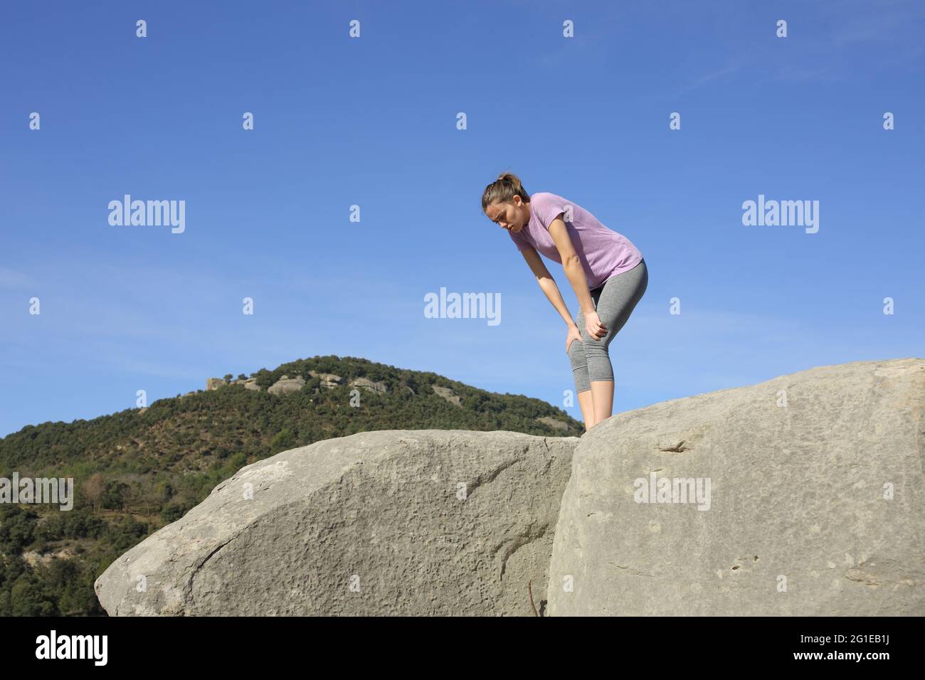 Exhausted runner resting in the top of a cliff after exercise in the ...