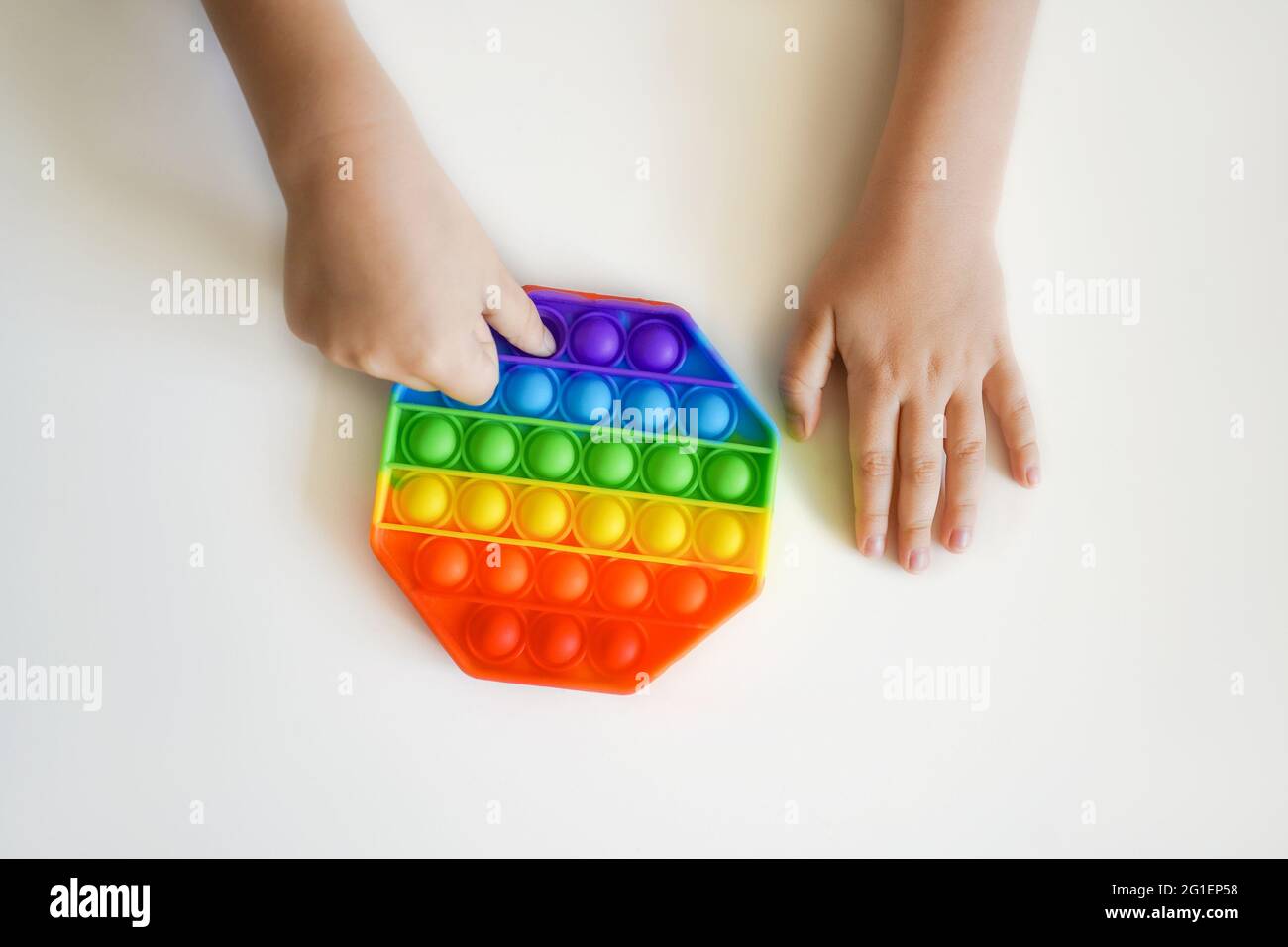 Pop it fidget in kid's hands. Colorful toy push pop it. Top view of ...