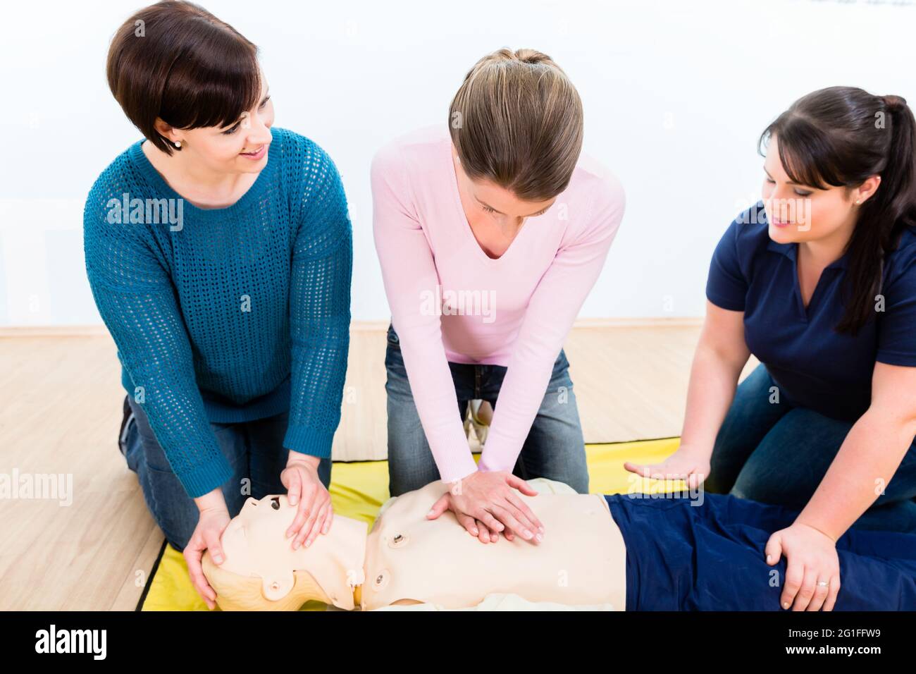 Group of women in first aid course exercising life-sustaining measures ...