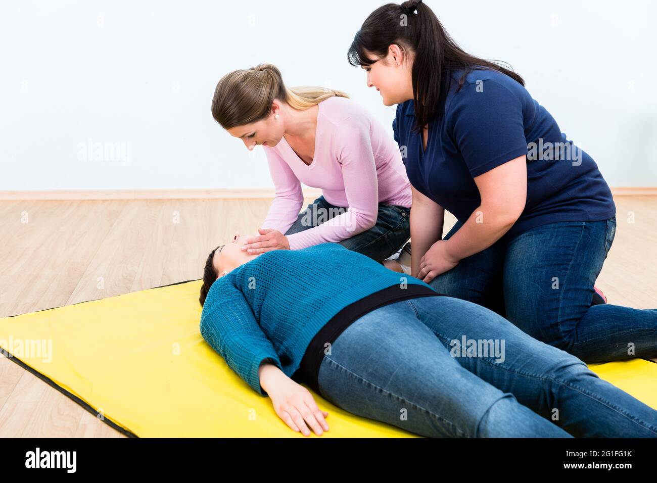 Women in first aid class training to position injured person Stock ...