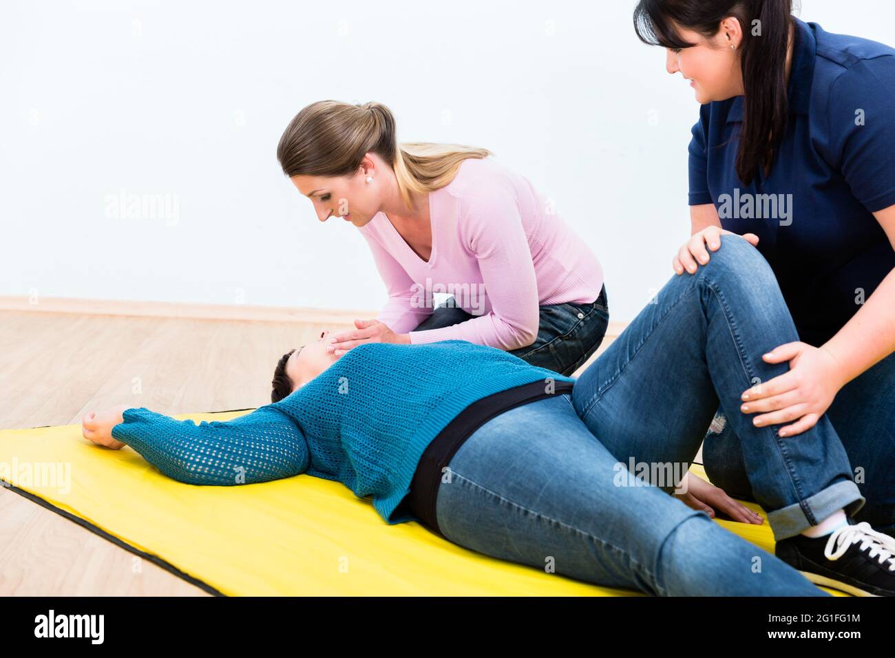 Women in first aid class training to position injured person Stock ...