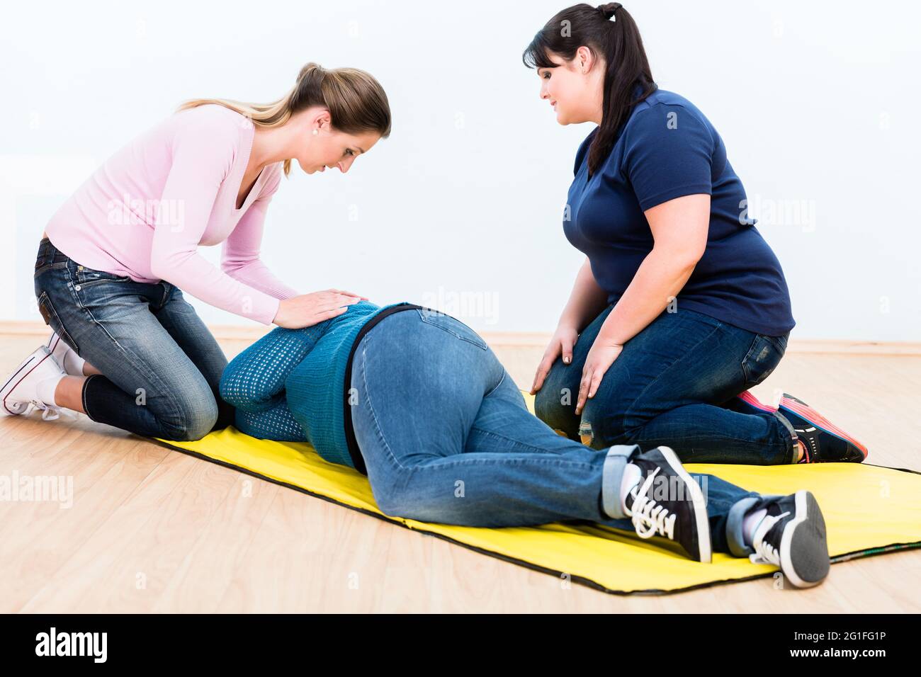 Women in first aid training learning to position injured person Stock ...