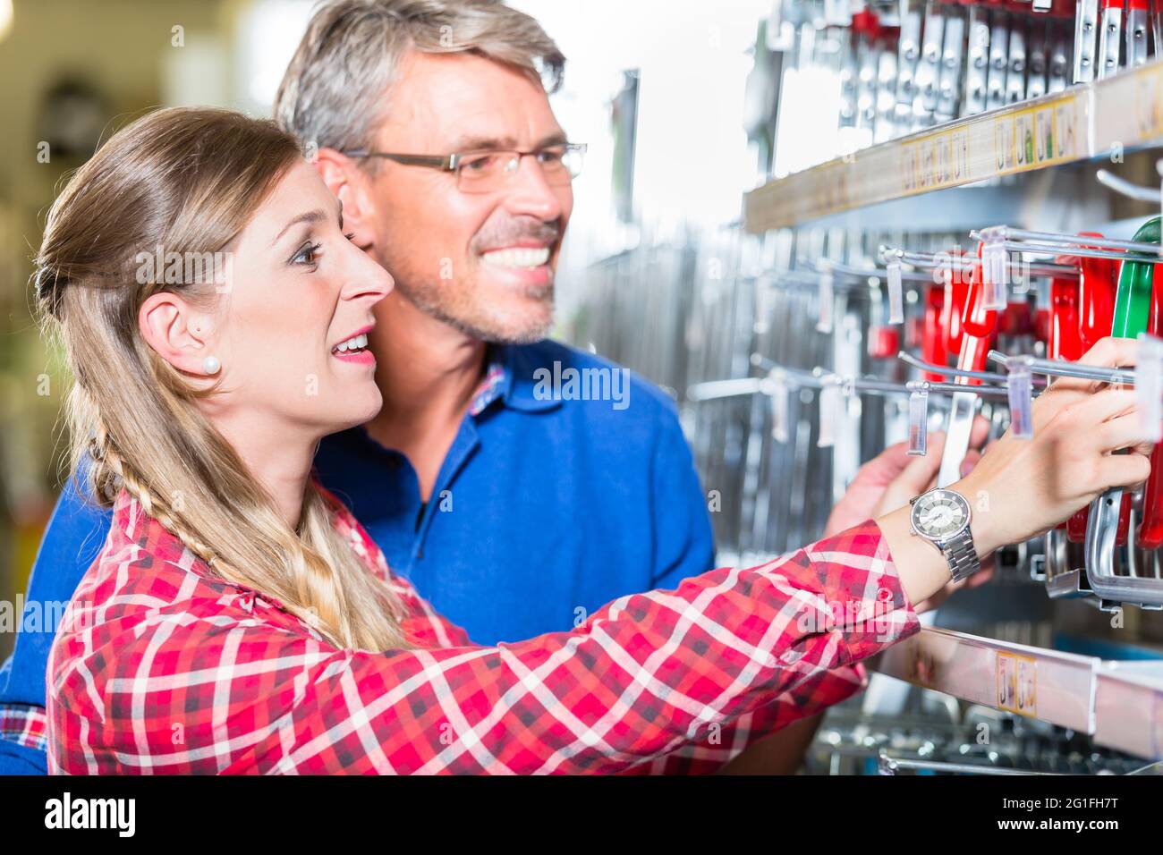 Young woman asking shop assistant in ironware department of hardware ...