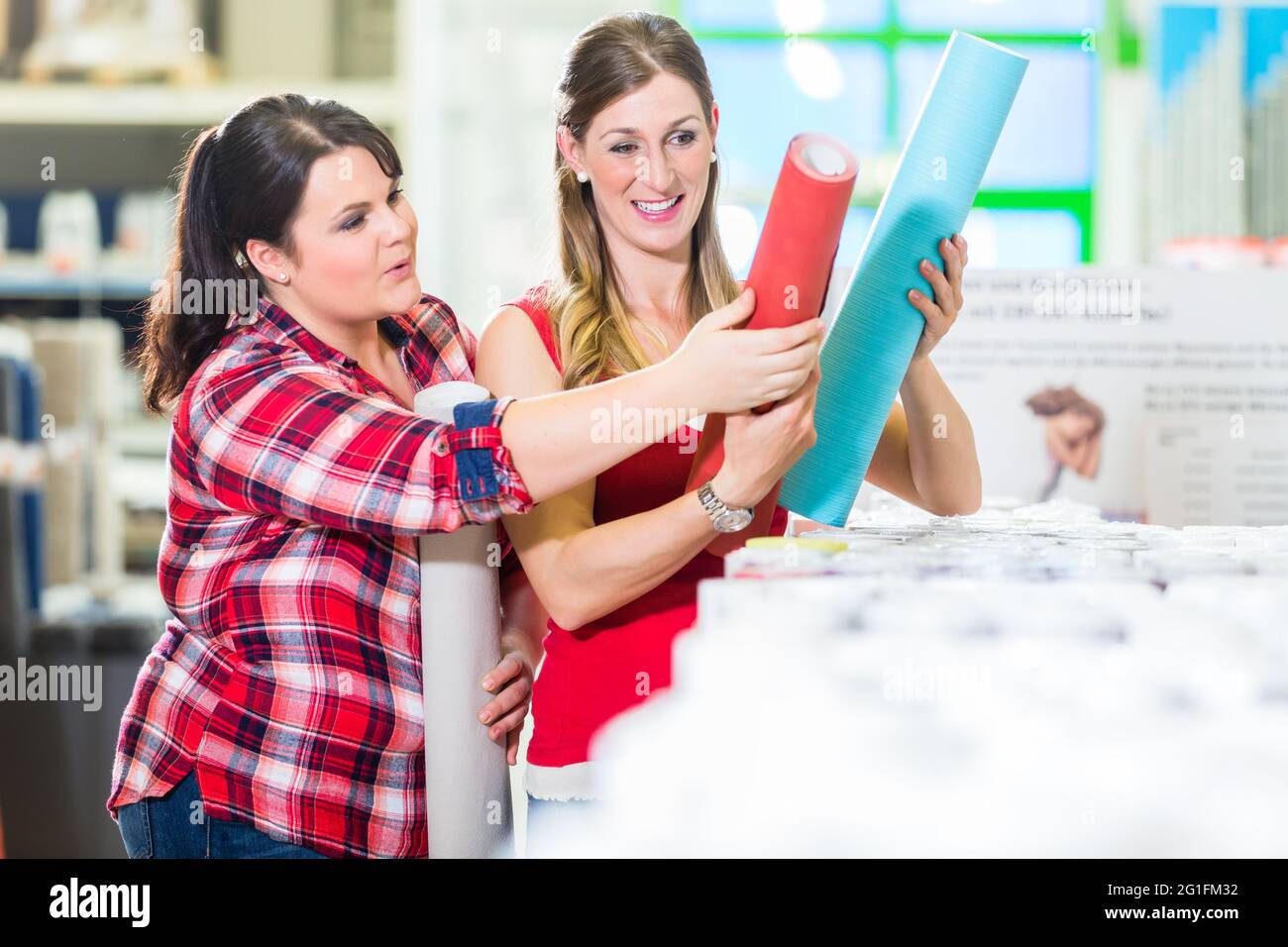 Young women in home improvement store choosing wallpapers for DIY ...