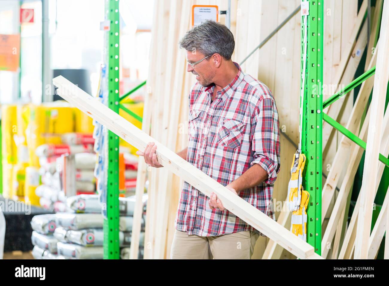 Customer in lumber department of hardware store choosing wood strip for ...