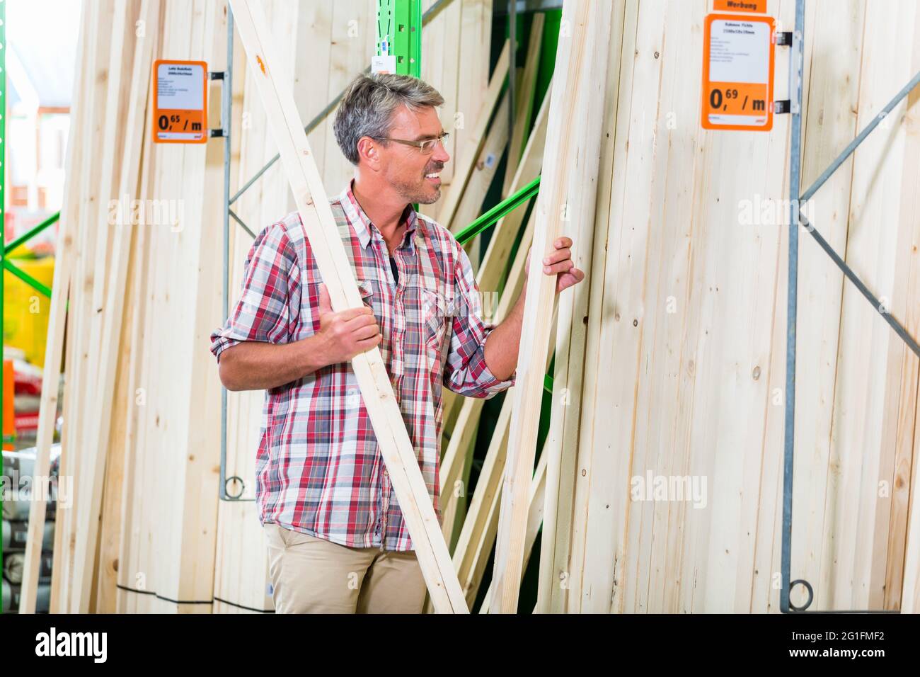Customer in lumber department of hardware store choosing wood strip for ...