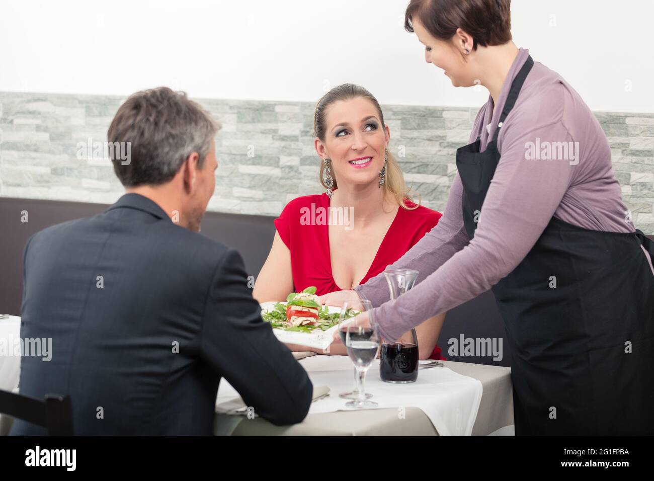 Female waitress placing order in front of couple Stock Photo - Alamy